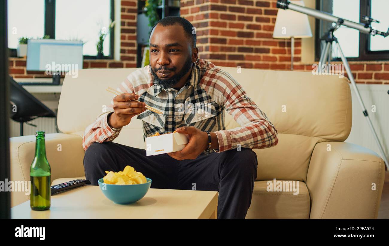 Happy adult serving noodles from box with chopsticks, eating asian food ...