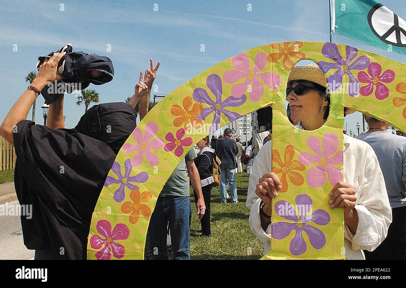 Laura Braly stands behind a cardboard peace sign and Julie Parker holds ...