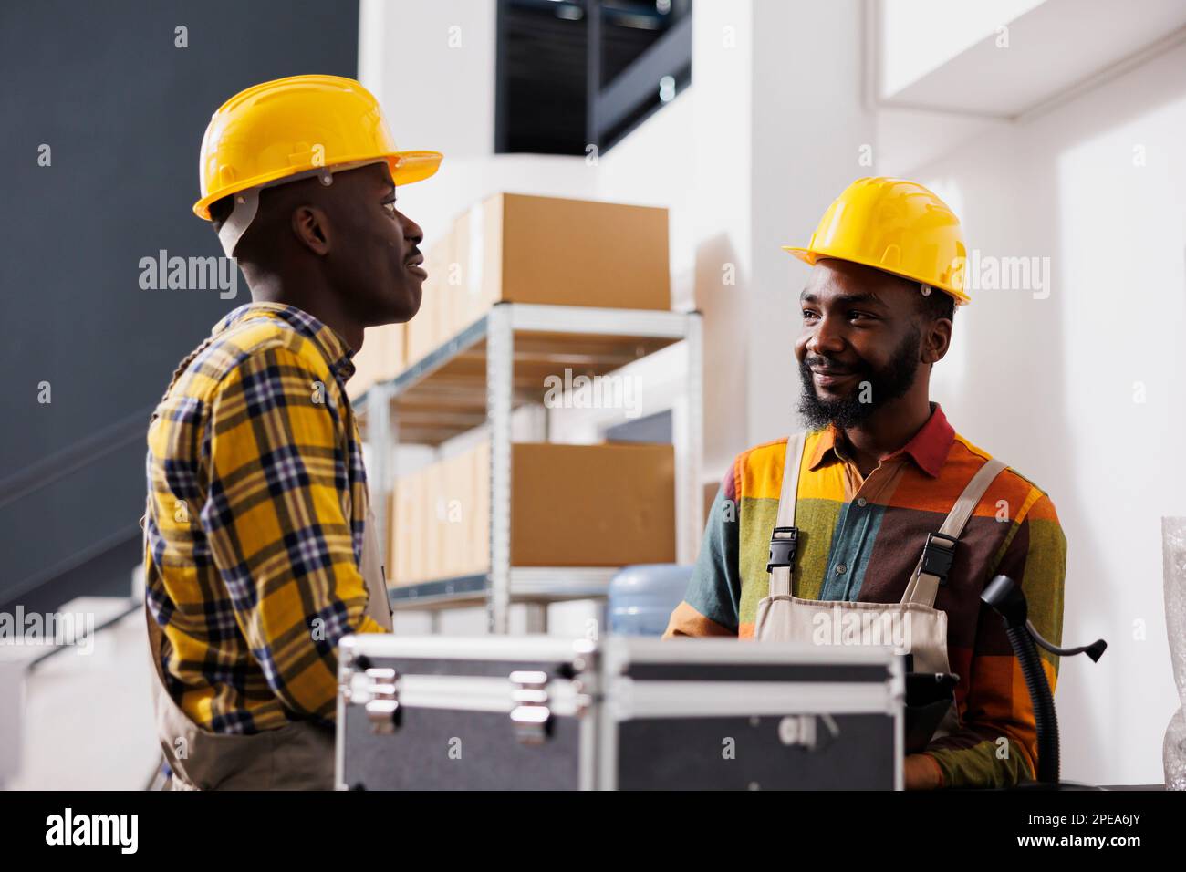 Two african american warehouse colleagues chatting at counter desk ...