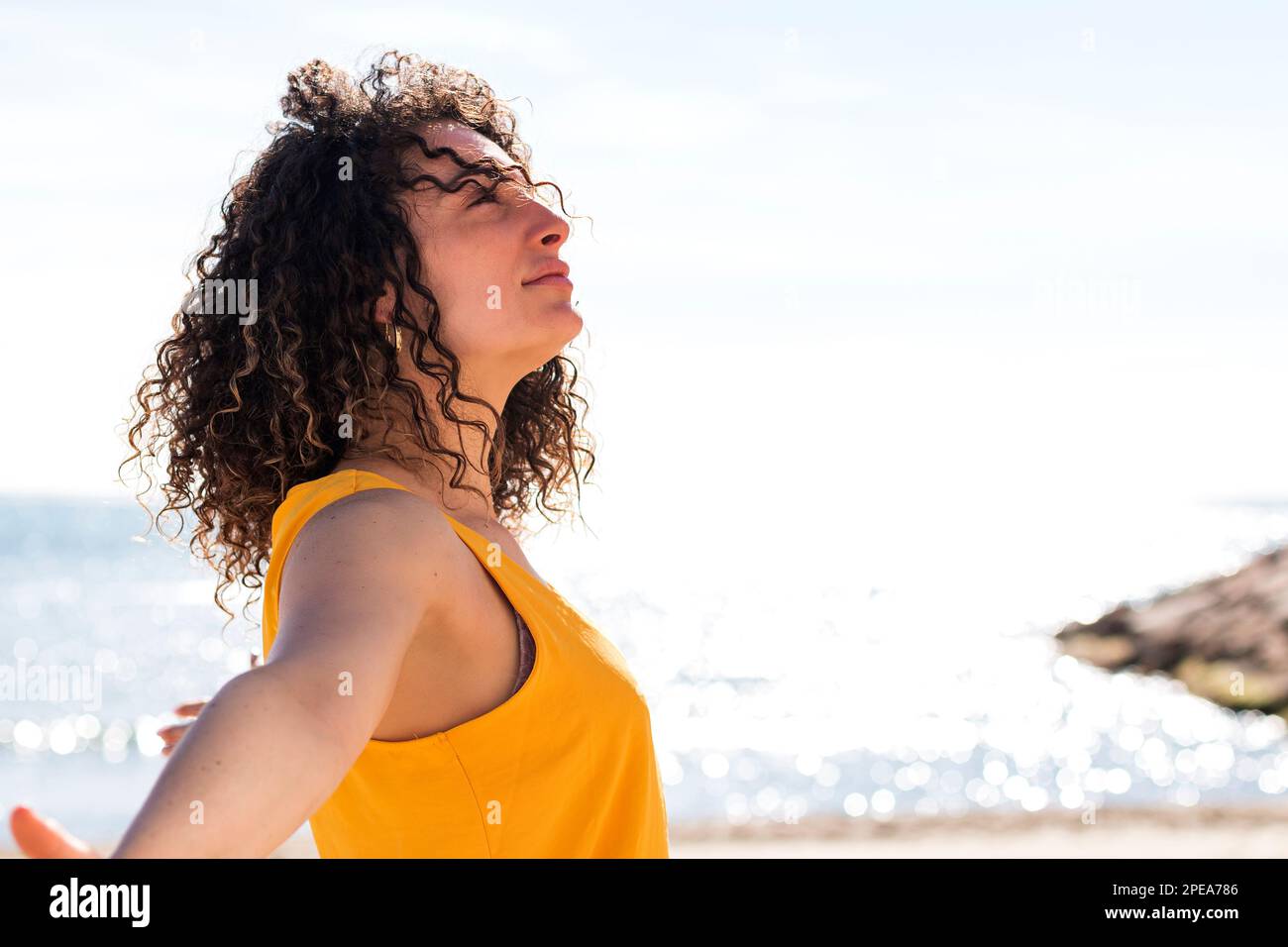 Side view of delighted woman with closed eyes spreading arms while ...
