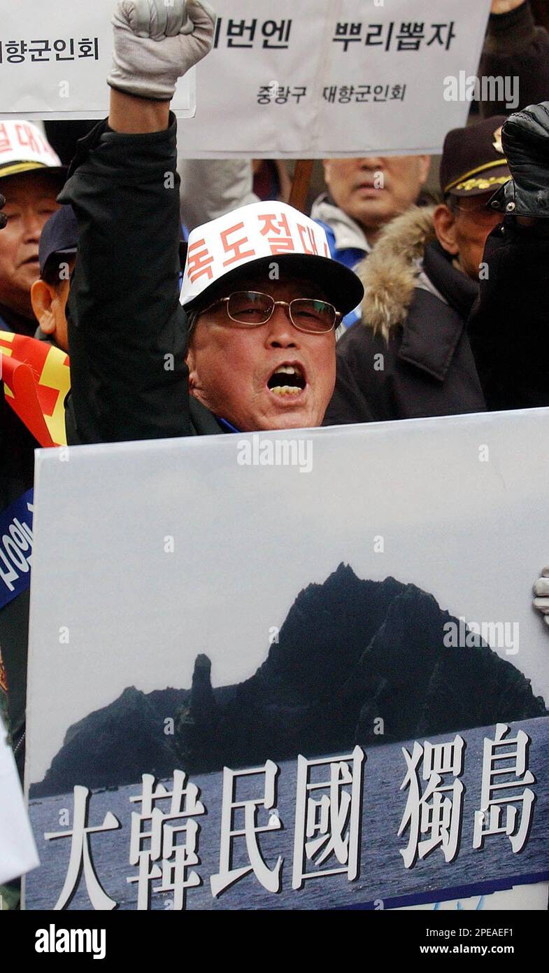 A Korean War veteran shouts slogans as he holds the picture of Dokdo ...