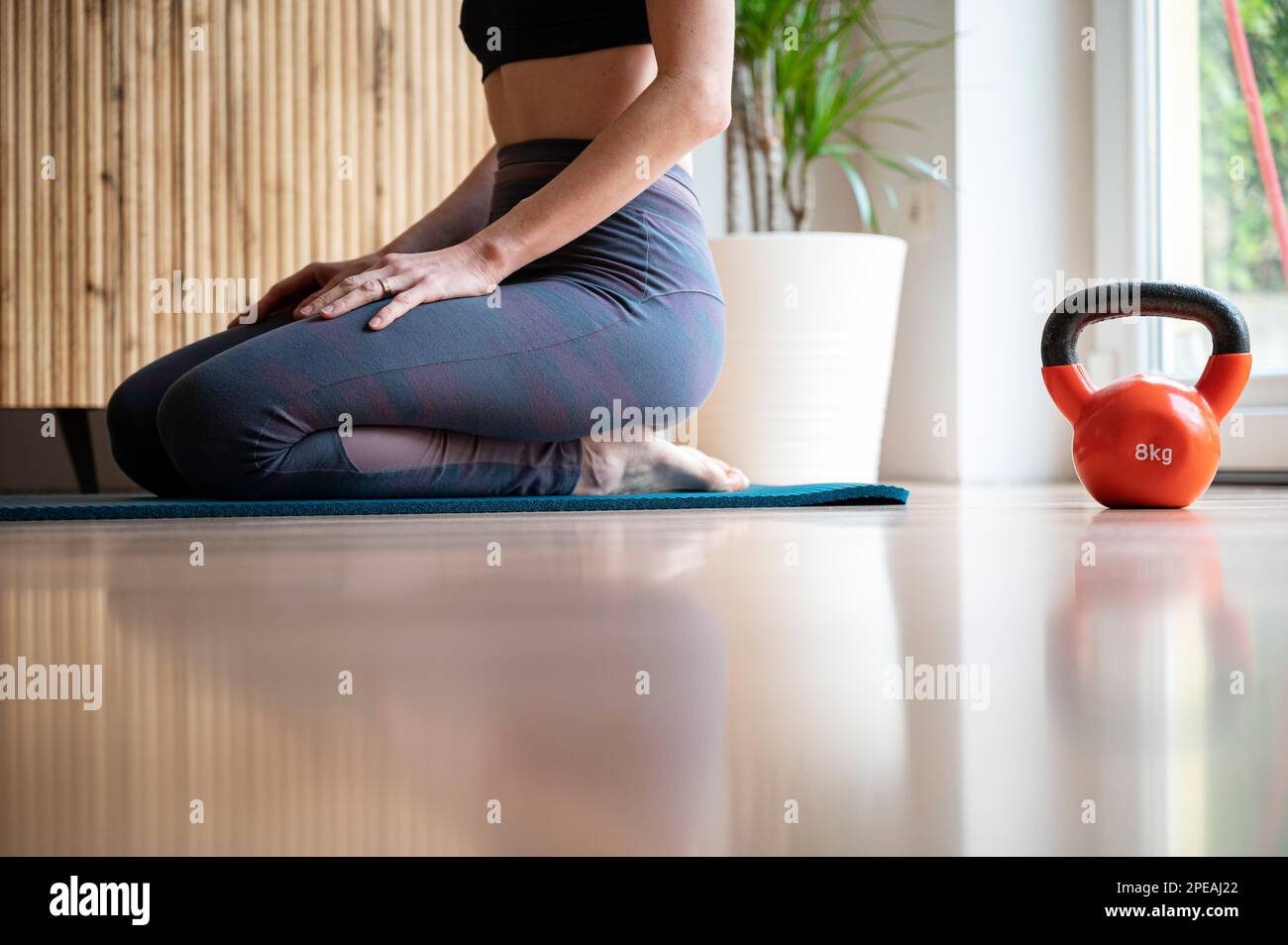 Fit woman sitting on an exercise mat taking a break from a home workout ...