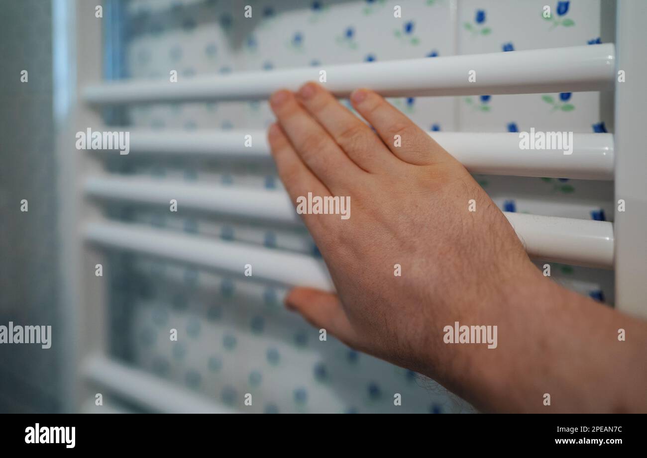 Man's hand checking temperature of heating radiator Stock Photo - Alamy