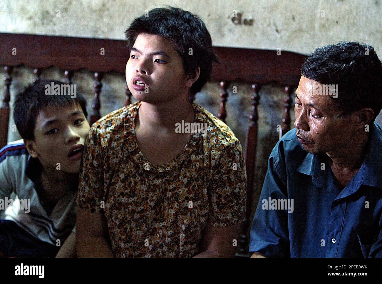 Nguyen Van Quy, 49, sits with his two children his son Nguyen Quang ...