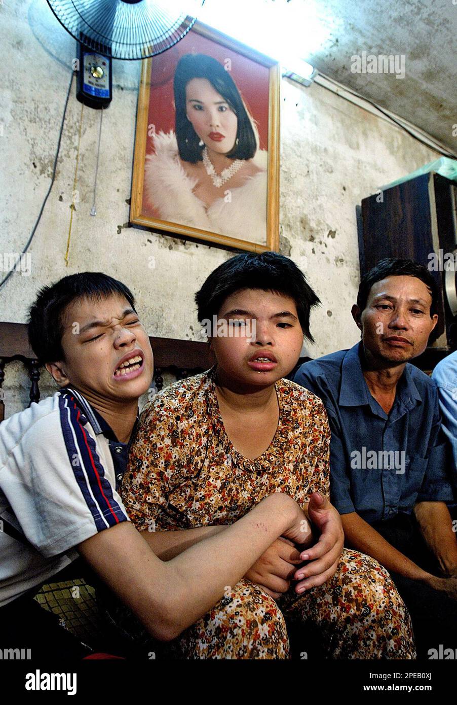 Nguyen Van Quy, 49, sits with his two children his son Nguyen Quang ...