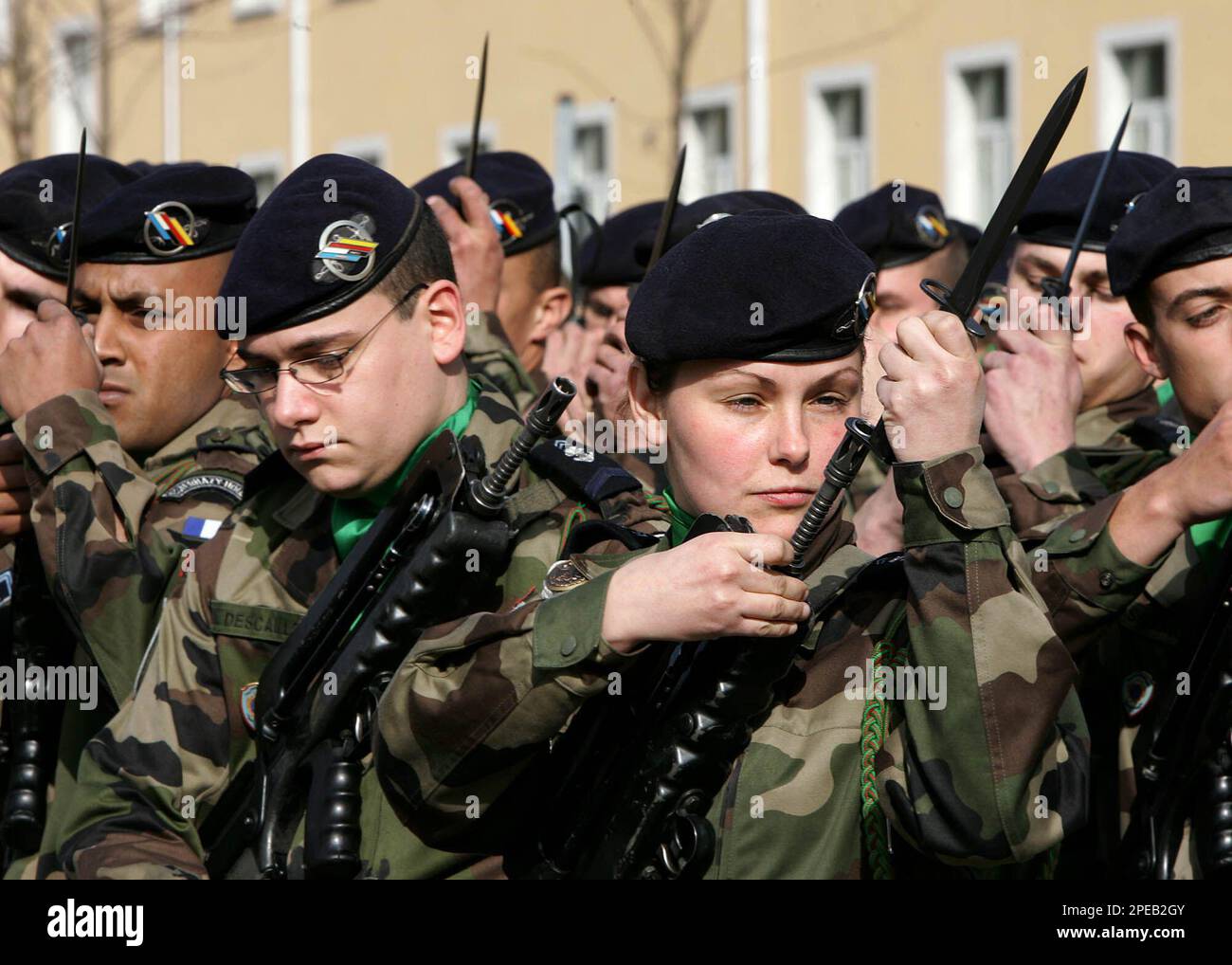 A female soldier attaches a bayonet to the barrel of her assault rifle ...