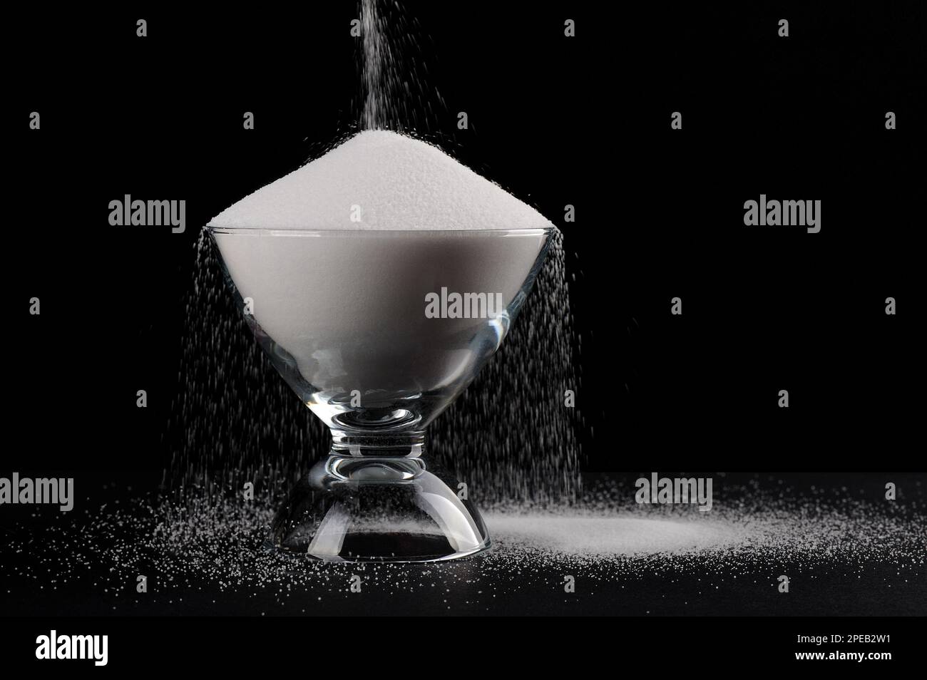 salt crystals filled to the top in a glass container on black ...