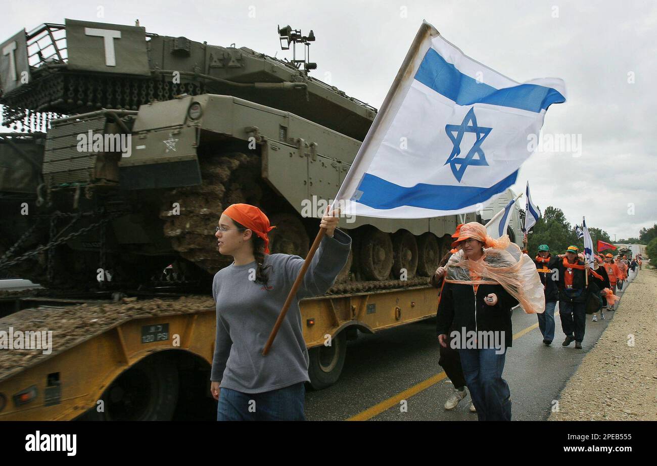 Holding Israeli flags, right wing protestors walk next to a tank during ...