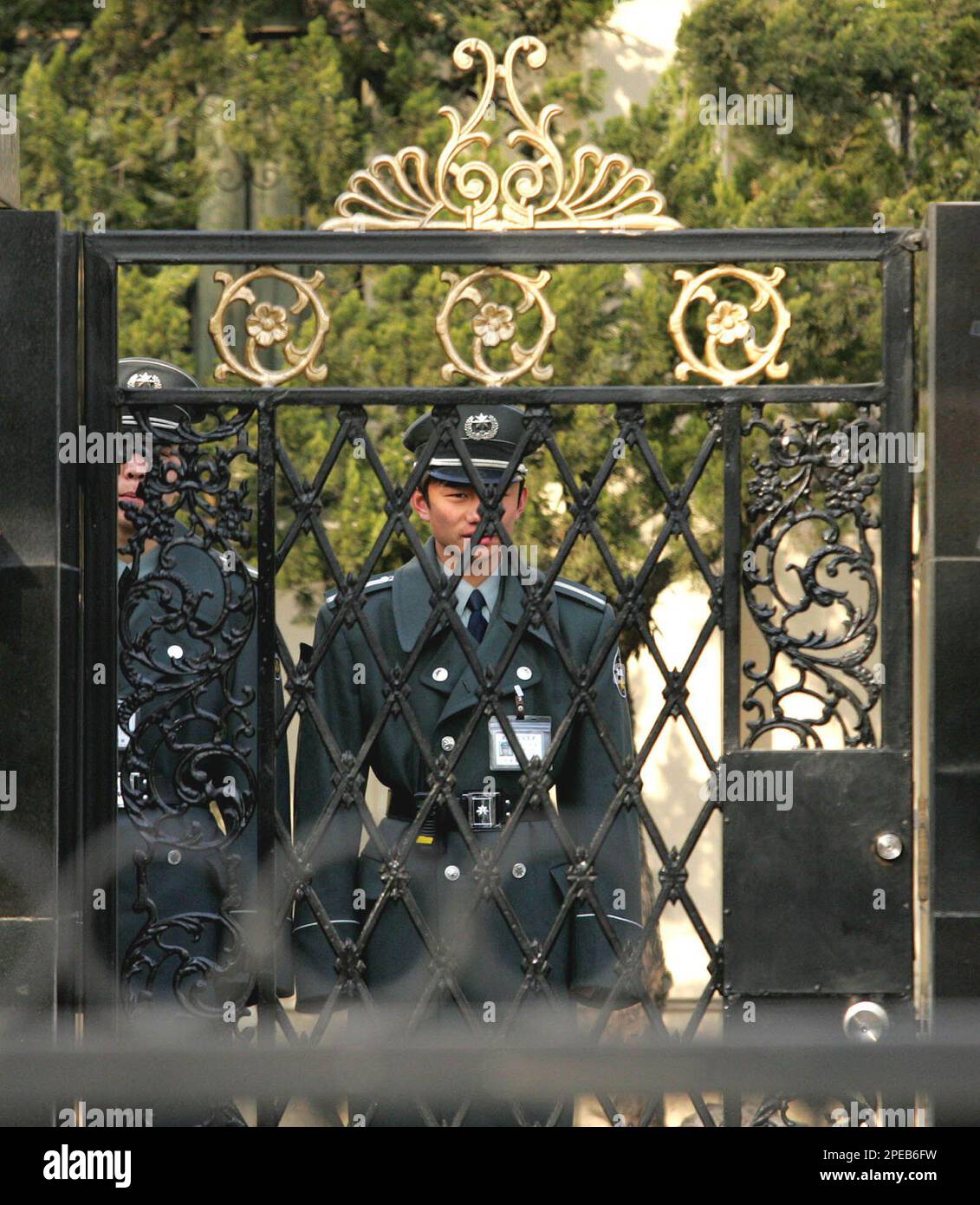 Chinese security guards stand inside the gate of the Japanese Embassy ...