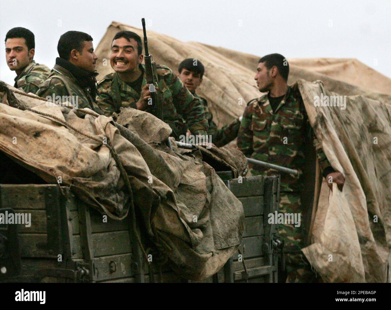 Syrian soldiers ride on a loaded army truck during a redeployment of ...