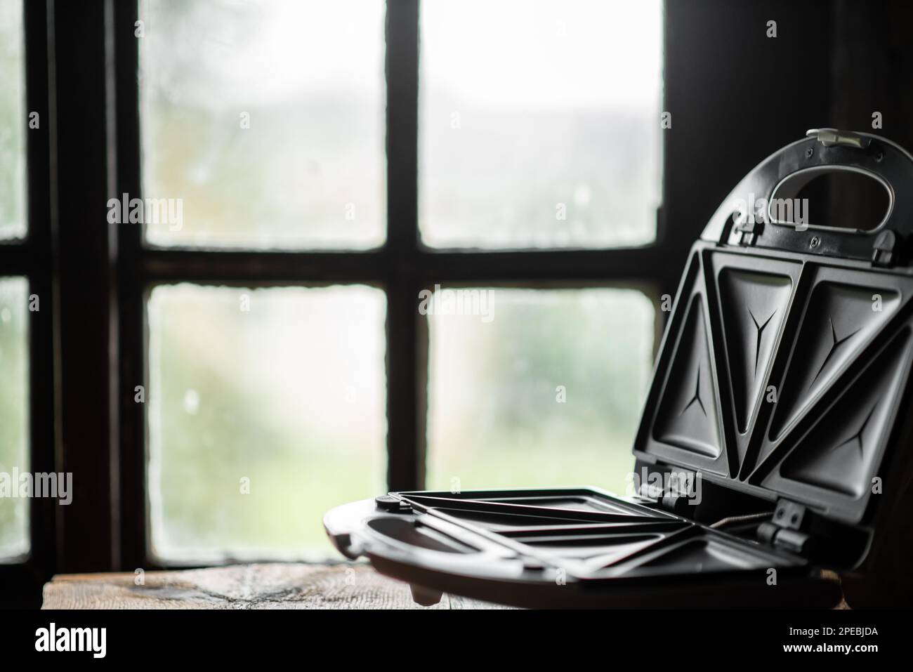 Open empty sandwich maker on the background of an old-fashioned house ...