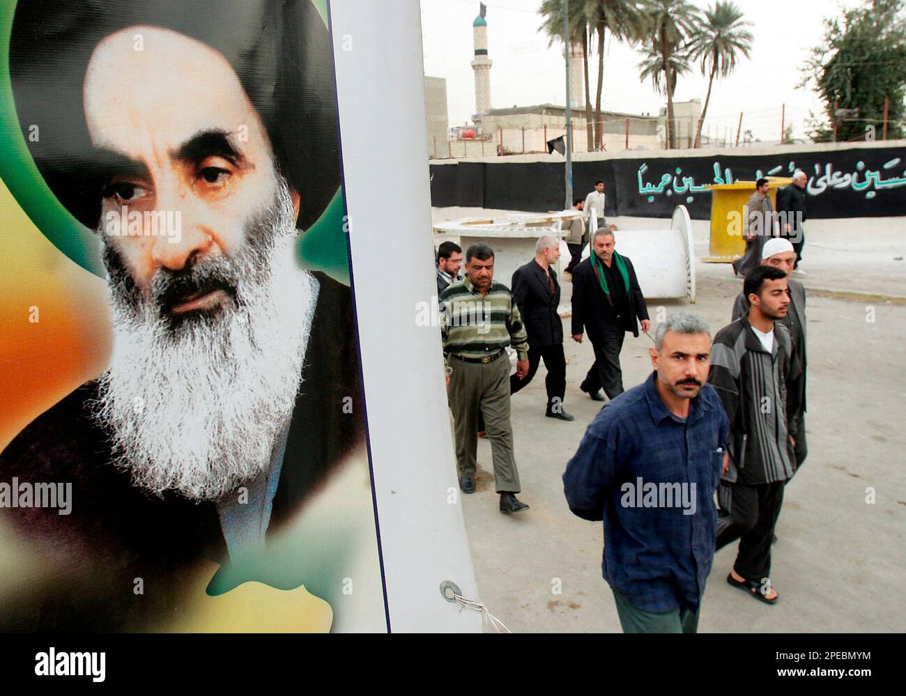 Shiite followers walk past a poster of their most revered leader, Grand ...