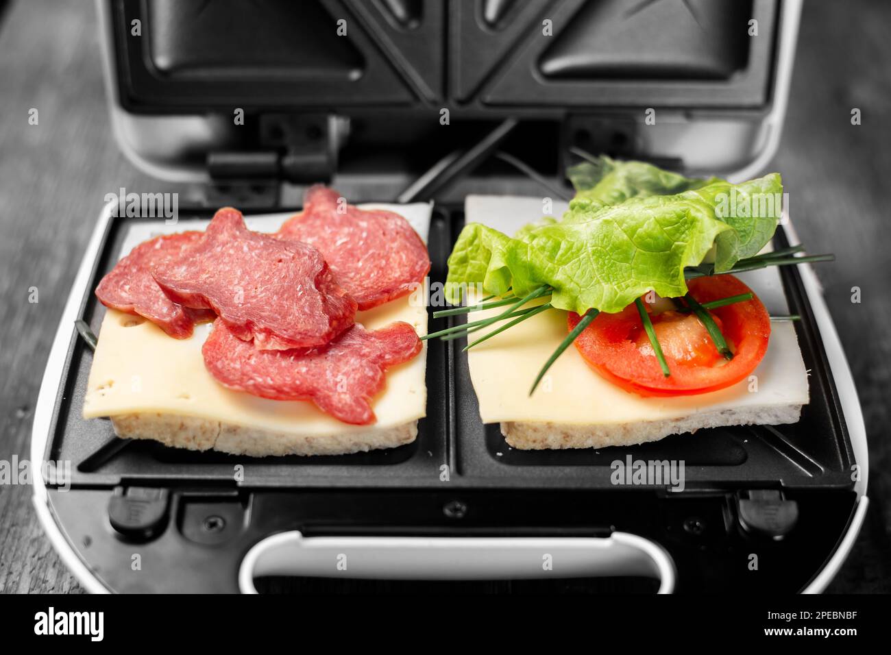 A sandwich maker with two different sandwiches with tomatoes, ham ...