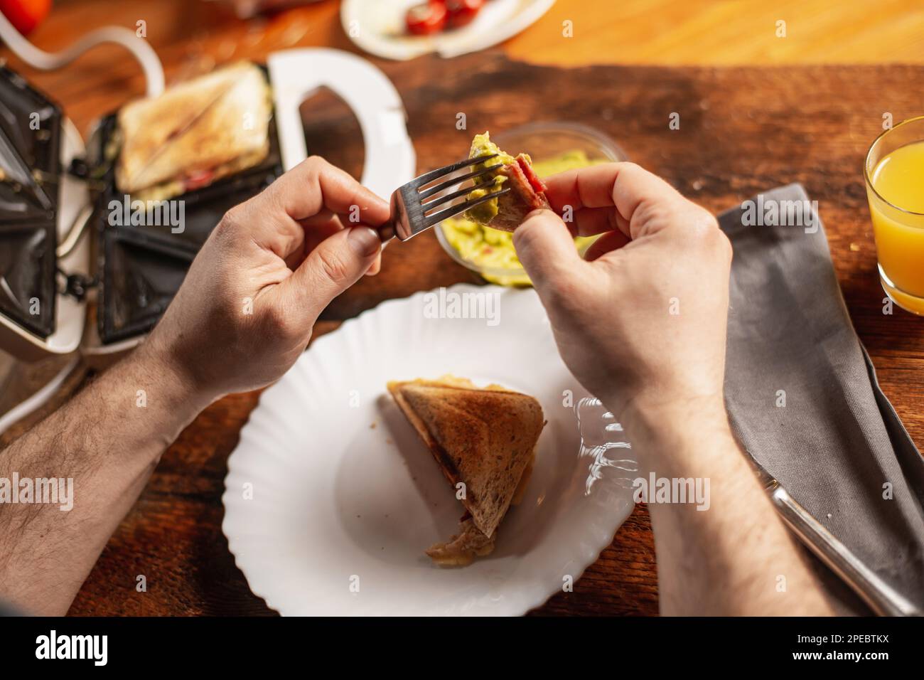unrecognizable man eats toast with guacamole. Breakfast time. The man's ...