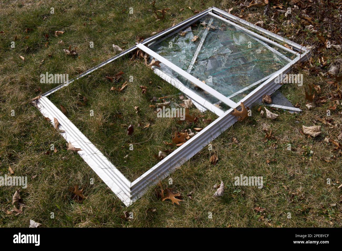 Fallen, broken window with lots of cracked glass on grass with some ...