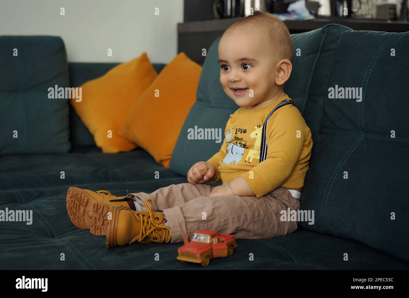 Adorable kid smiling and sitting on couch Stock Photo - Alamy
