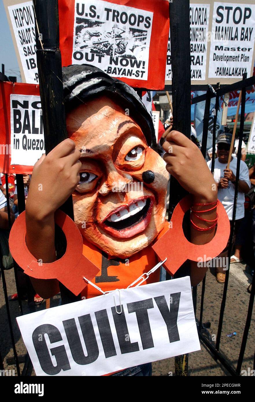 A protester wearing a mask of Philippine President Gloria Macapagal ...
