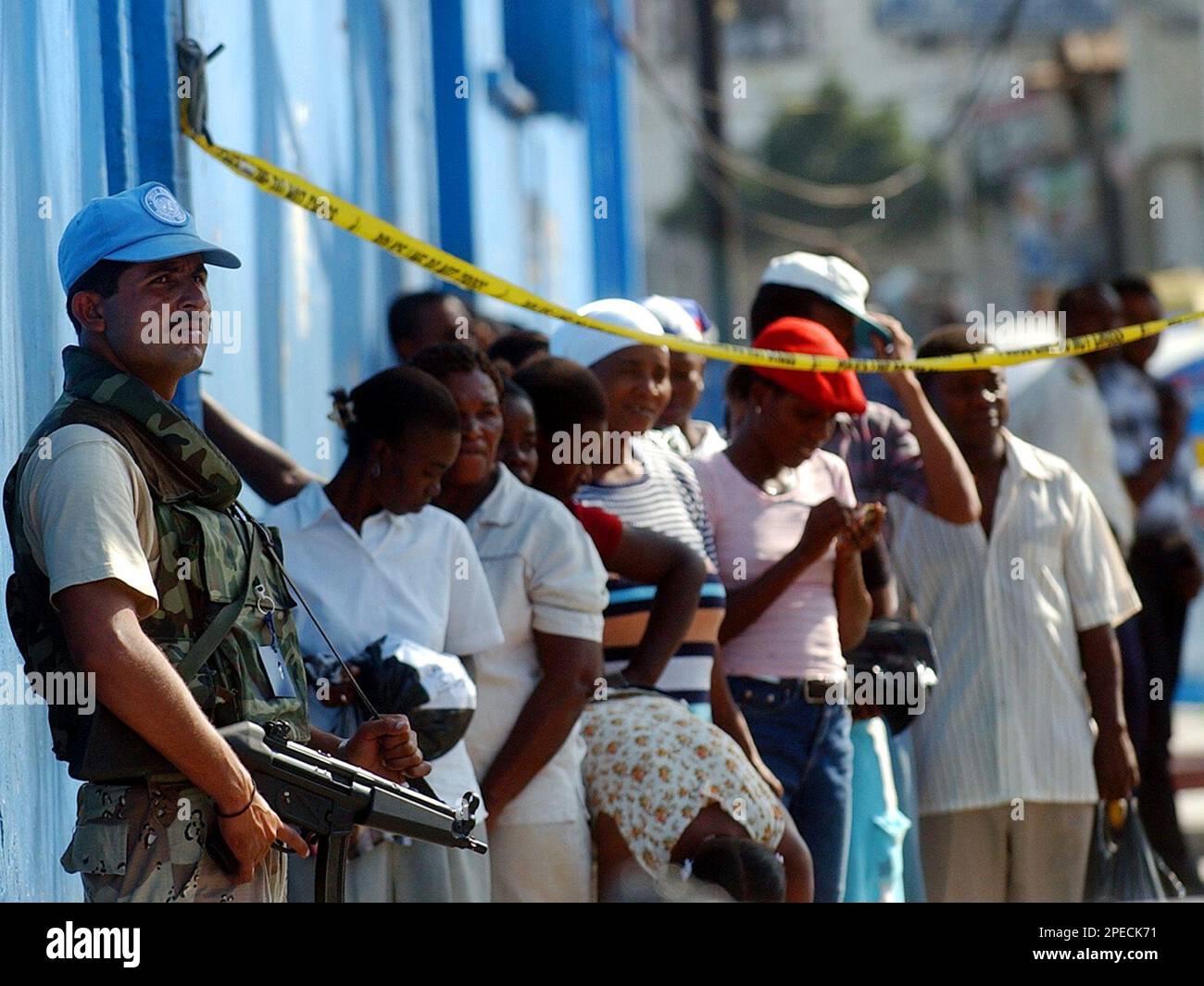 A U.N. peacekeeper from Pakistan stands guard as Haitians wait in line ...