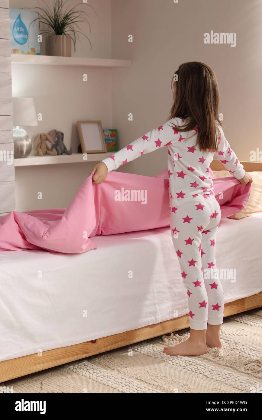 Cute little girl making bed at home Stock Photo - Alamy