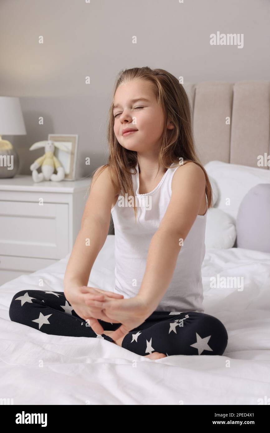 Cute little girl stretching on bed at home Stock Photo - Alamy