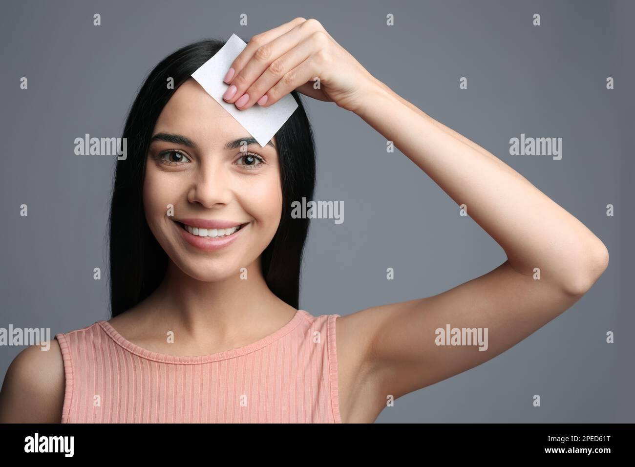 Beautiful woman using mattifying wipe on grey background Stock Photo ...