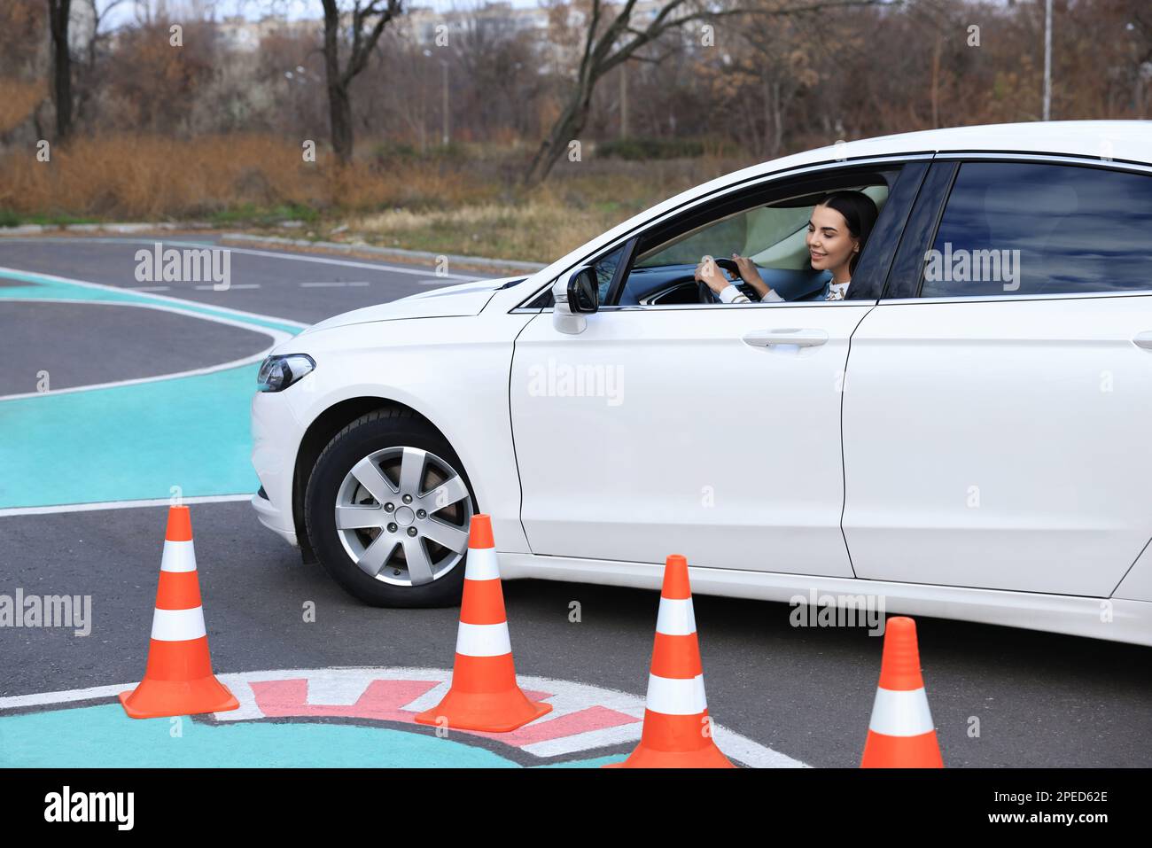 Young woman in car on test track with traffic cones. Driving school ...