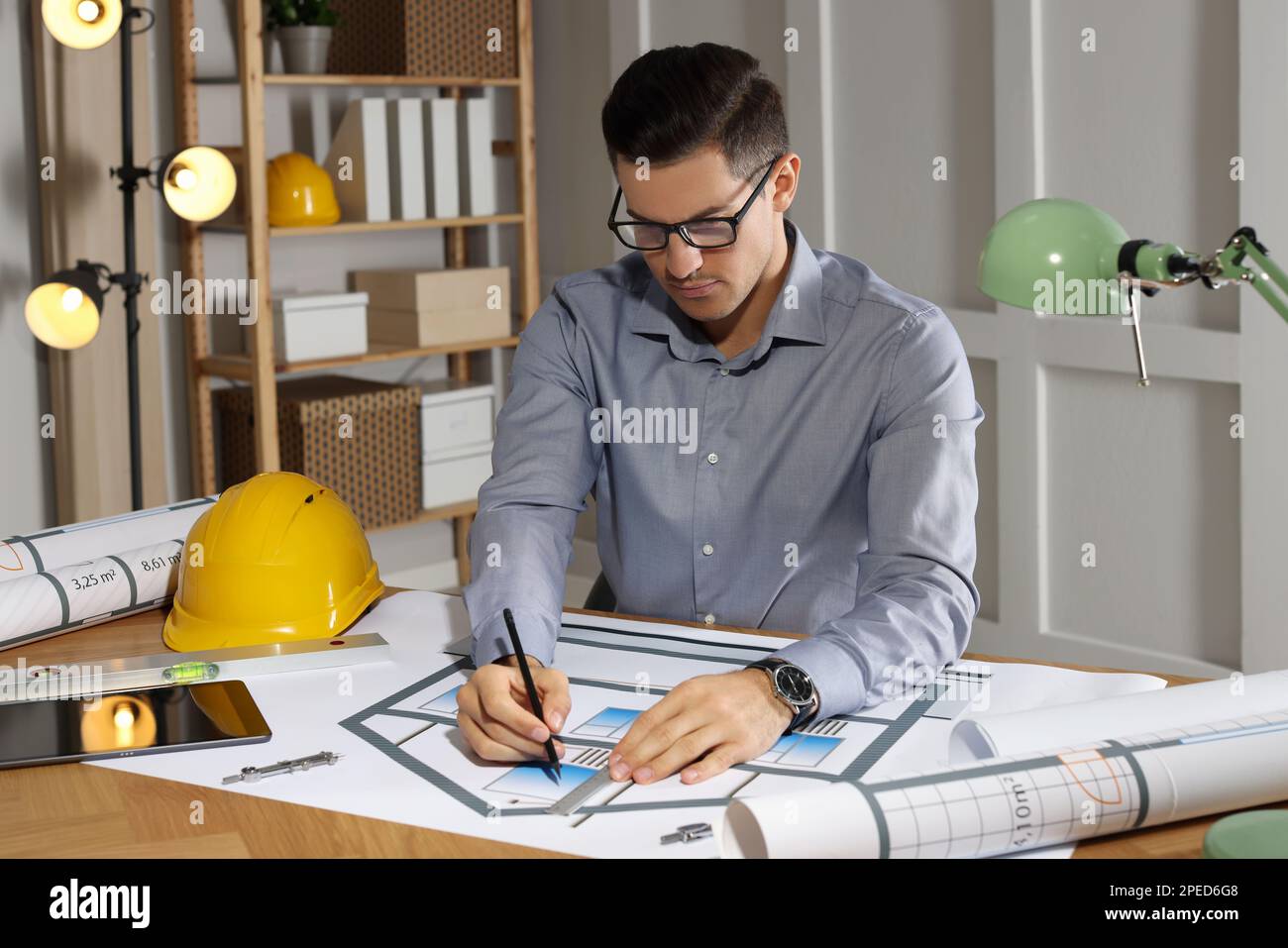 Architect working with construction drawings in office Stock Photo - Alamy