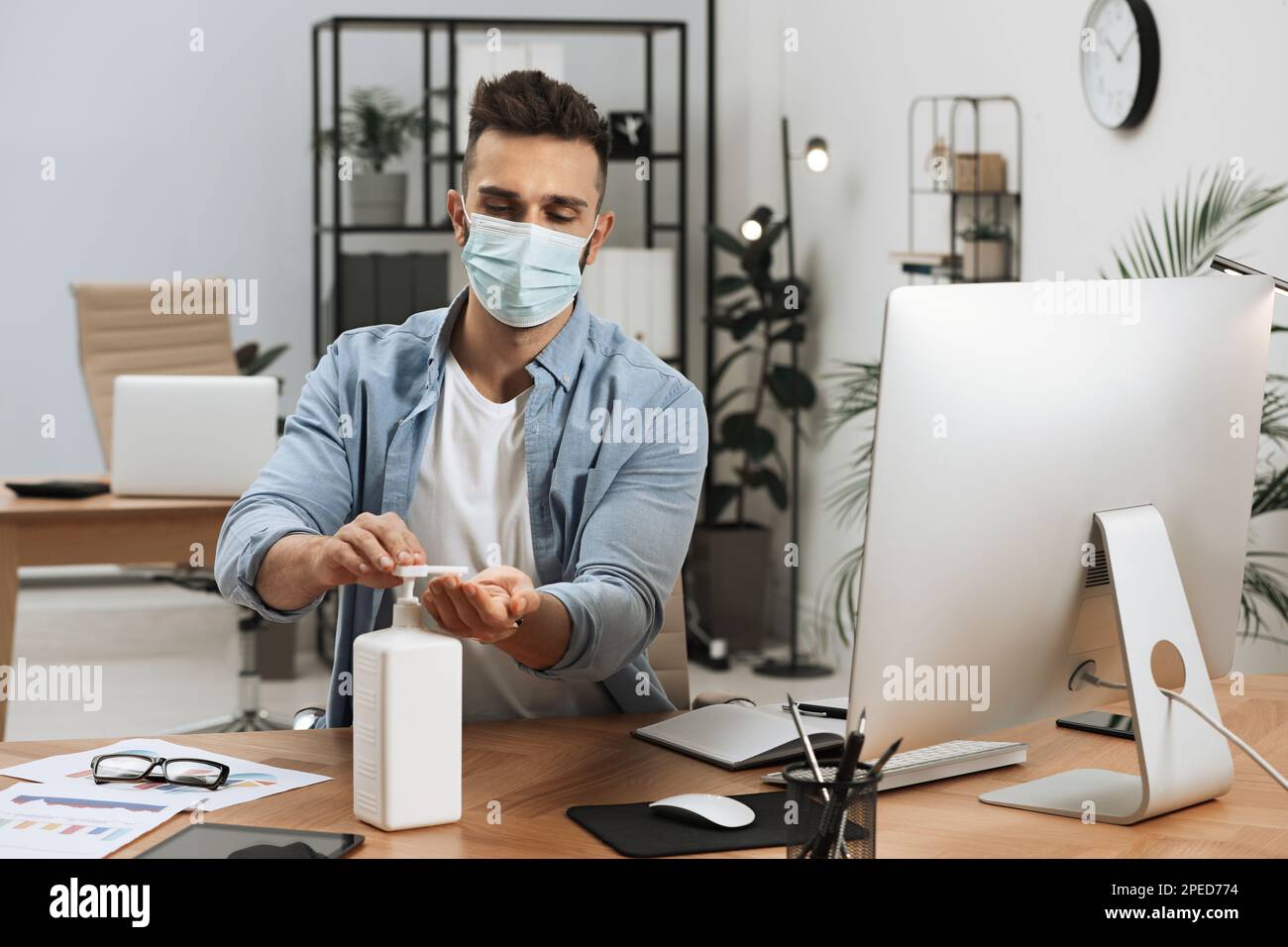 Man applying hand sanitizer at workplace in office. Personal hygiene ...