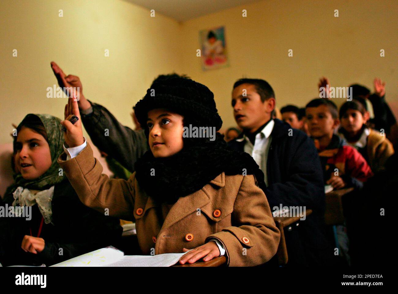 Fourth grade pupils raise their hands during the Arabic language class ...