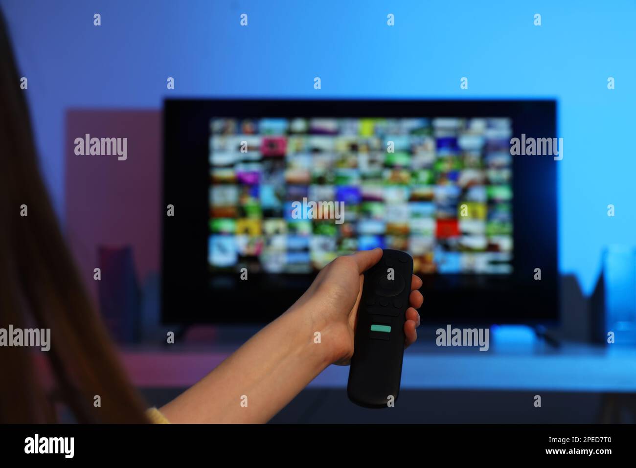 Woman switching channels on TV set with remote control at home, closeup ...