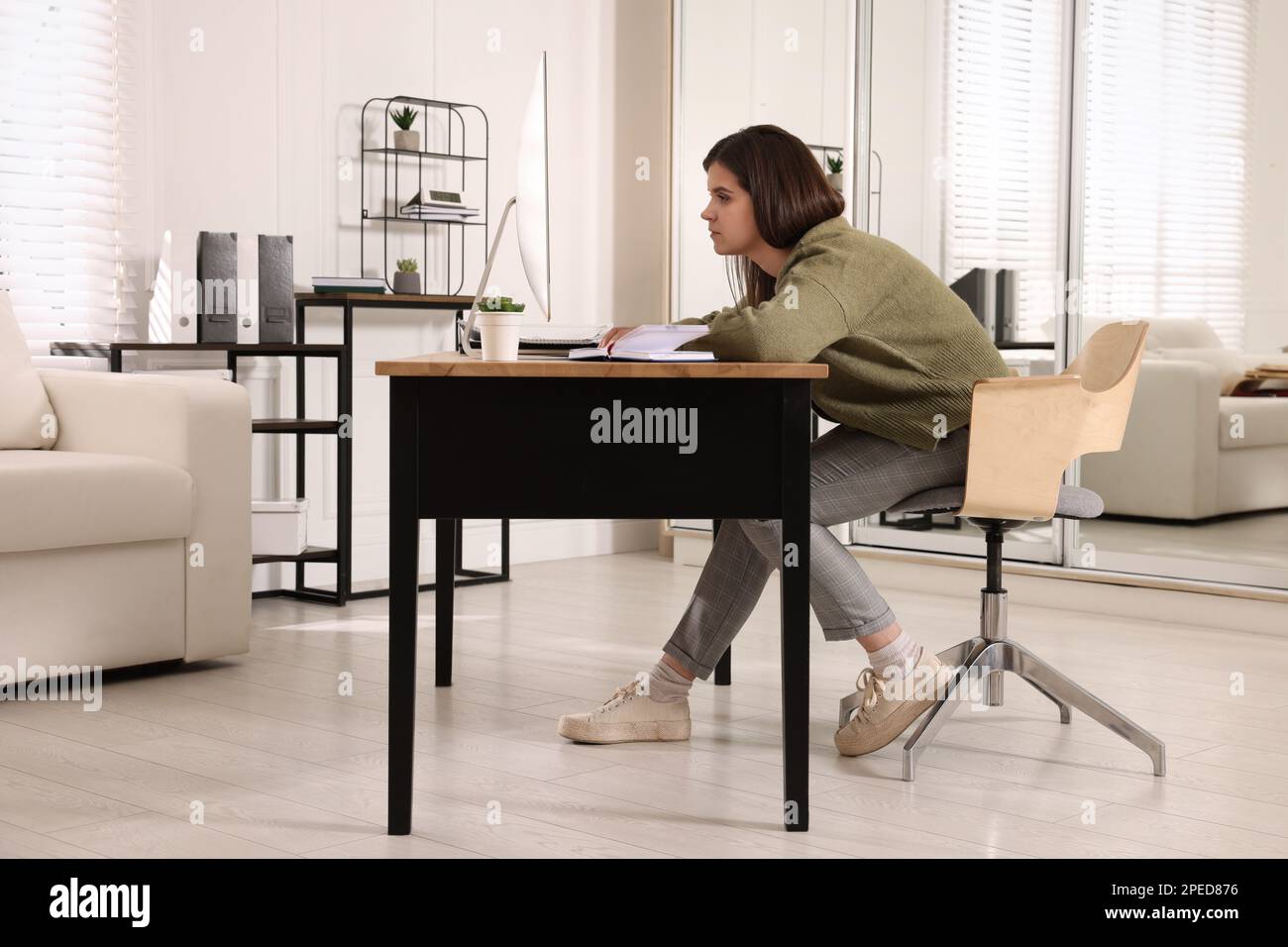 Young woman with bad posture working at table in office Stock Photo - Alamy