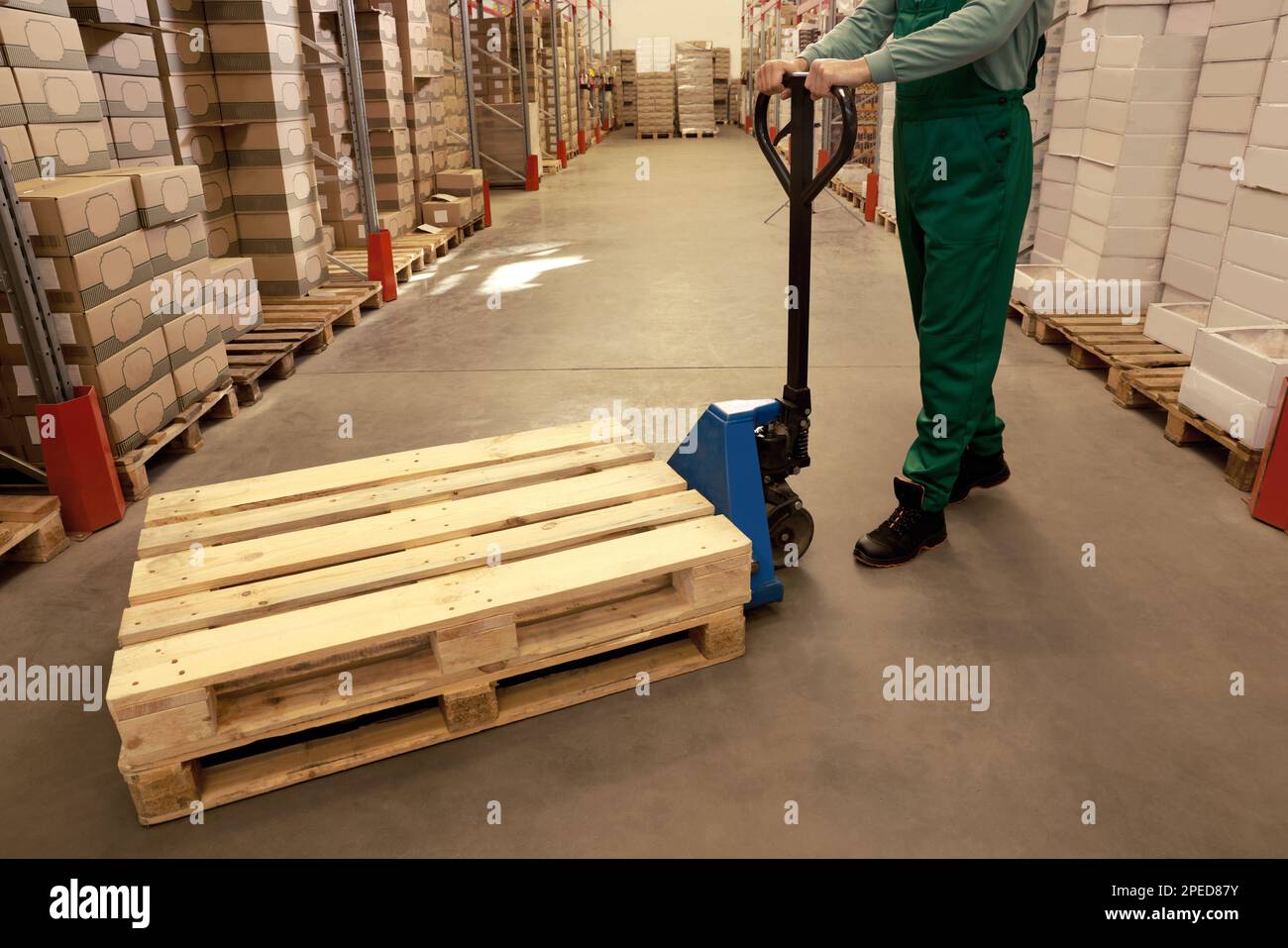 Worker moving wooden pallets with manual forklift in warehouse, closeup ...