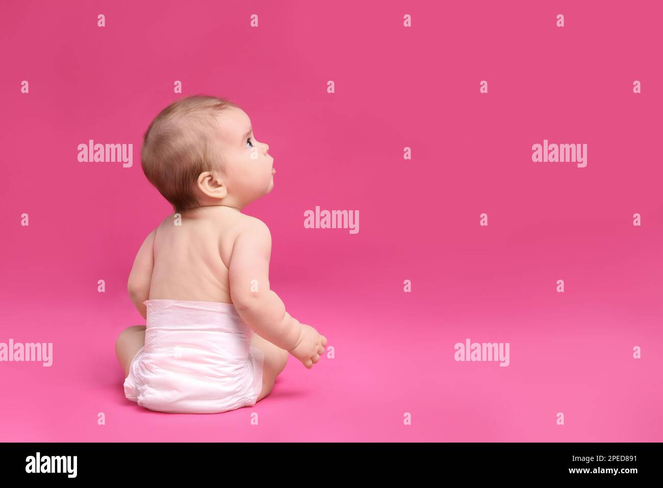 Cute little baby in diaper sitting on pink background, back view. Space ...