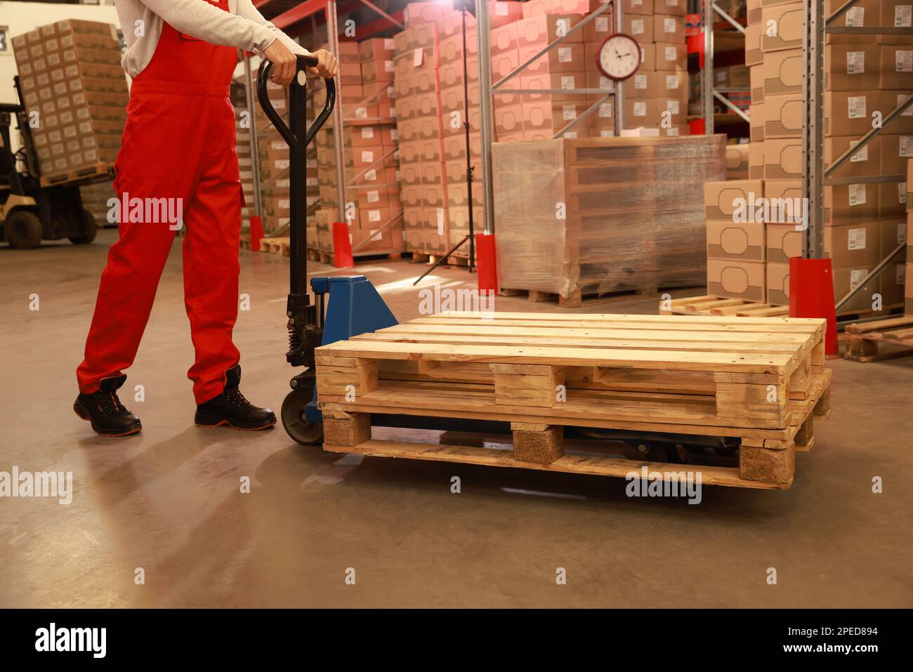Worker moving wooden pallets with manual forklift in warehouse, closeup ...