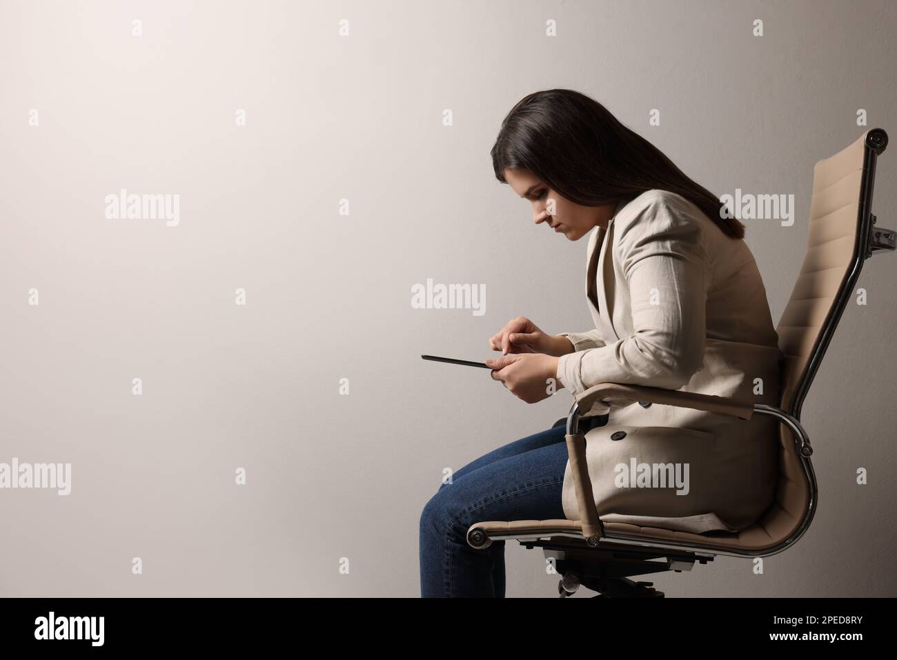 Young woman with bad posture using tablet while sitting on chair ...