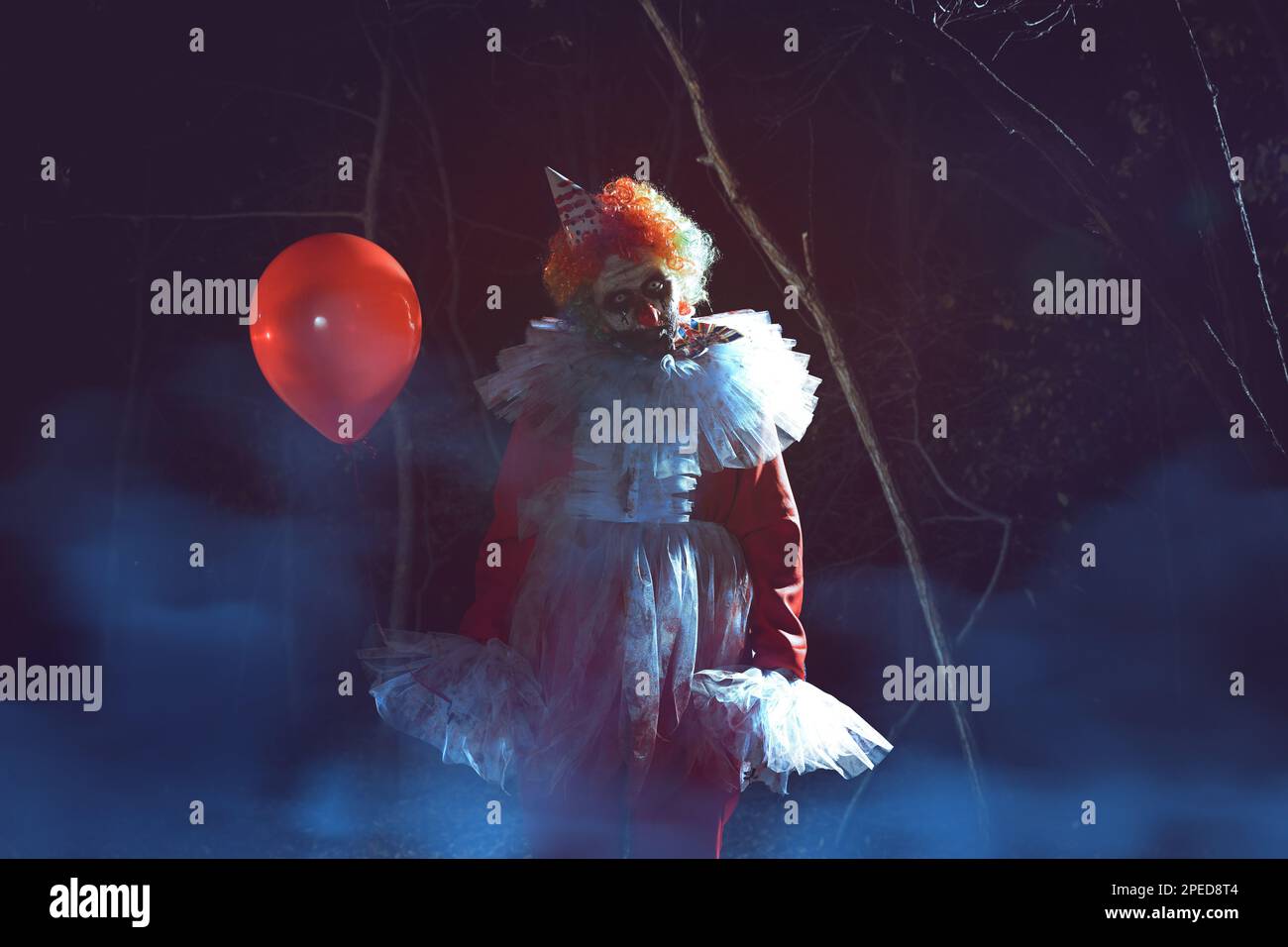 Terrifying clown with red air balloon outdoors at night. Halloween ...