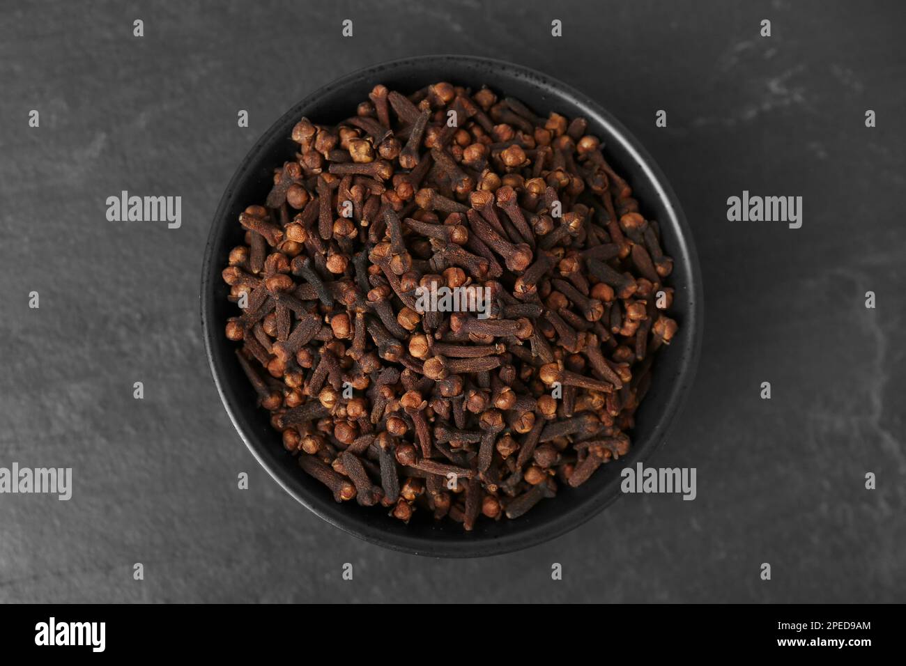 Bowl of aromatic dry cloves on black table, top view Stock Photo - Alamy
