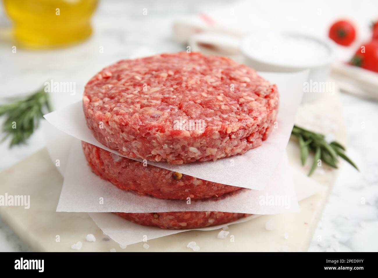 Raw hamburger patties with rosemary and salt on board, closeup Stock ...