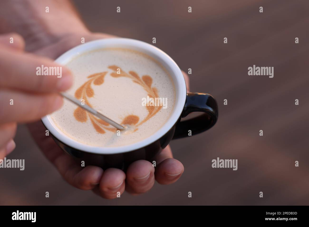 Barista creating pattern in cup of coffee on blurred background ...