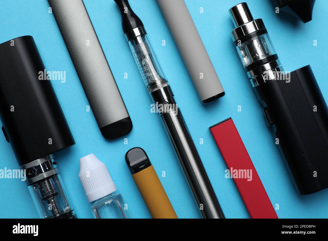 Different electronic cigarettes and liquid solution on light blue ...