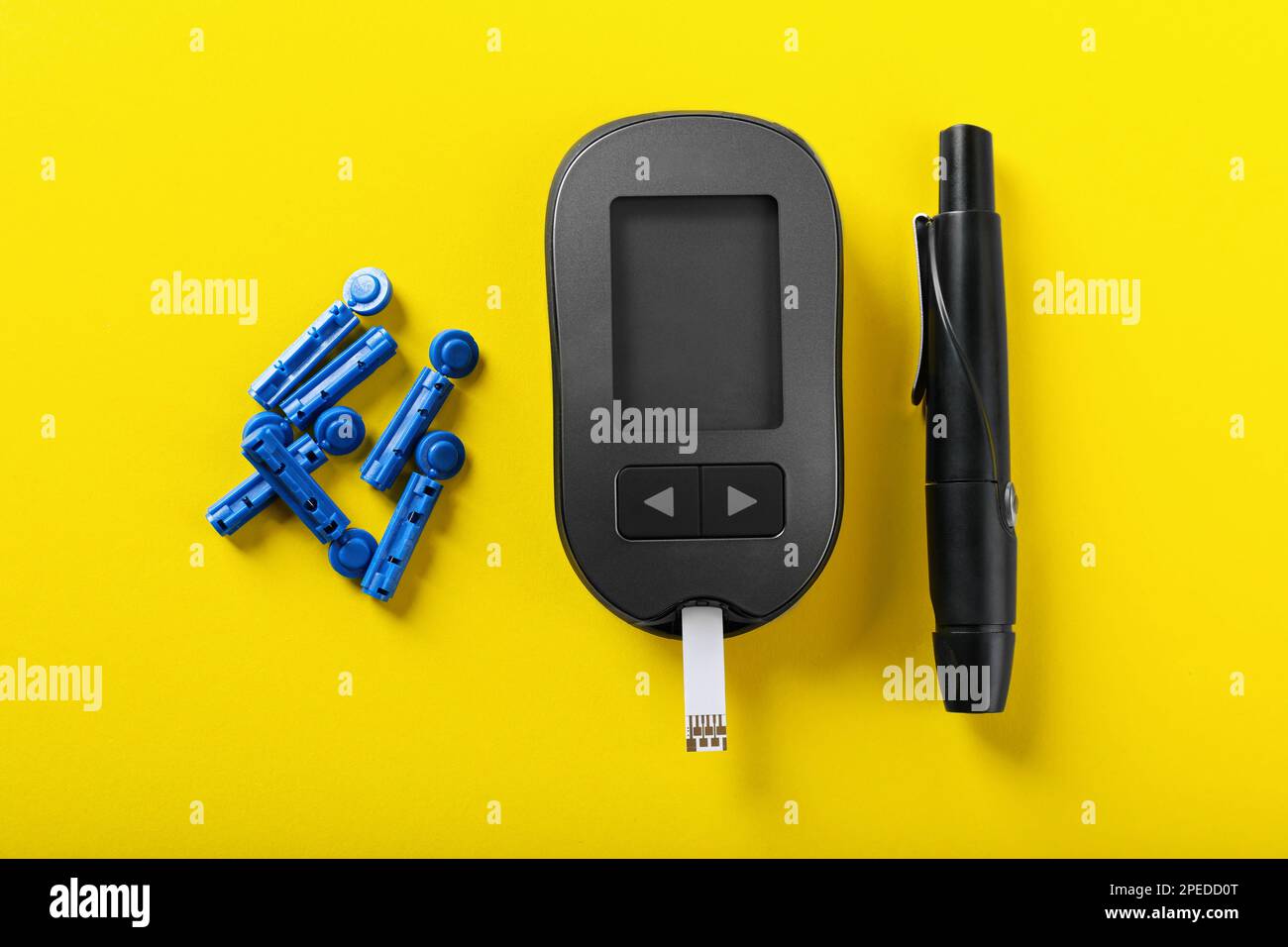 Digital glucometer with test strip, lancets and pen on yellow ...
