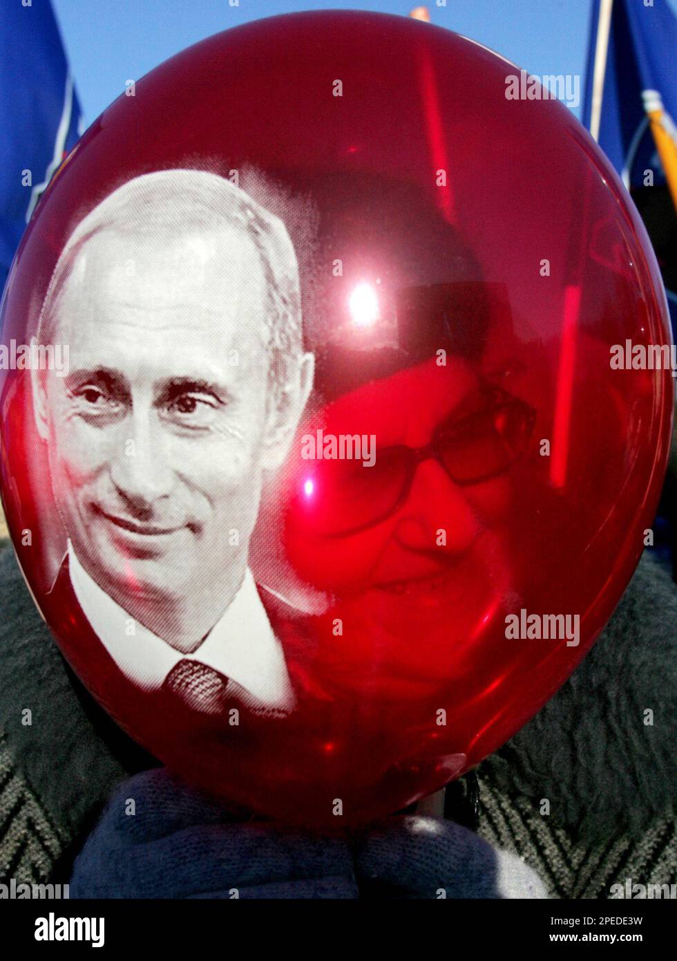 An elderly demonstrator holds a balloon with Putin's portrait during a ...