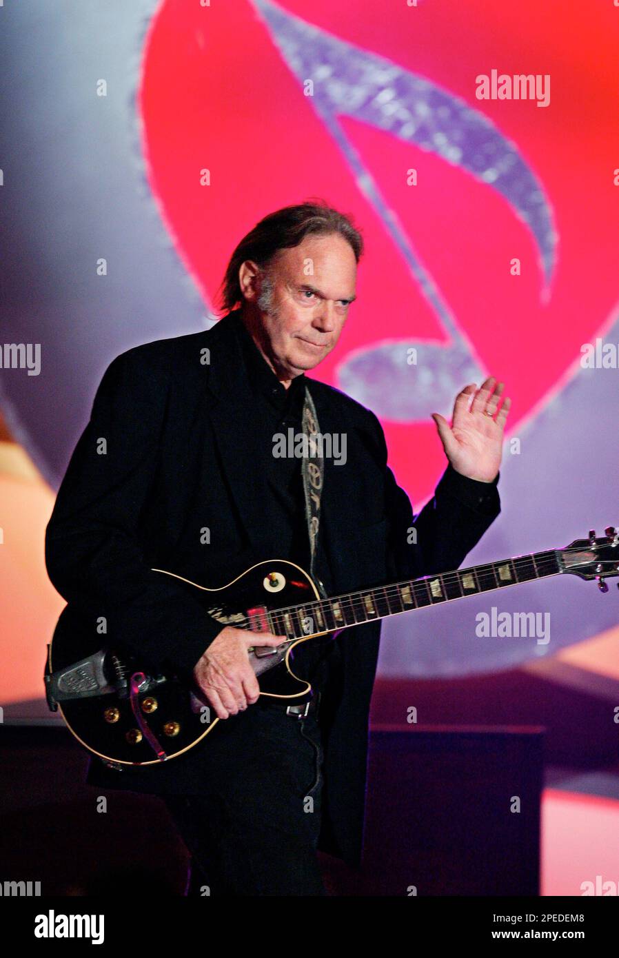 Neil Young acknowledges the crowd as he takes the stage to perform the ...