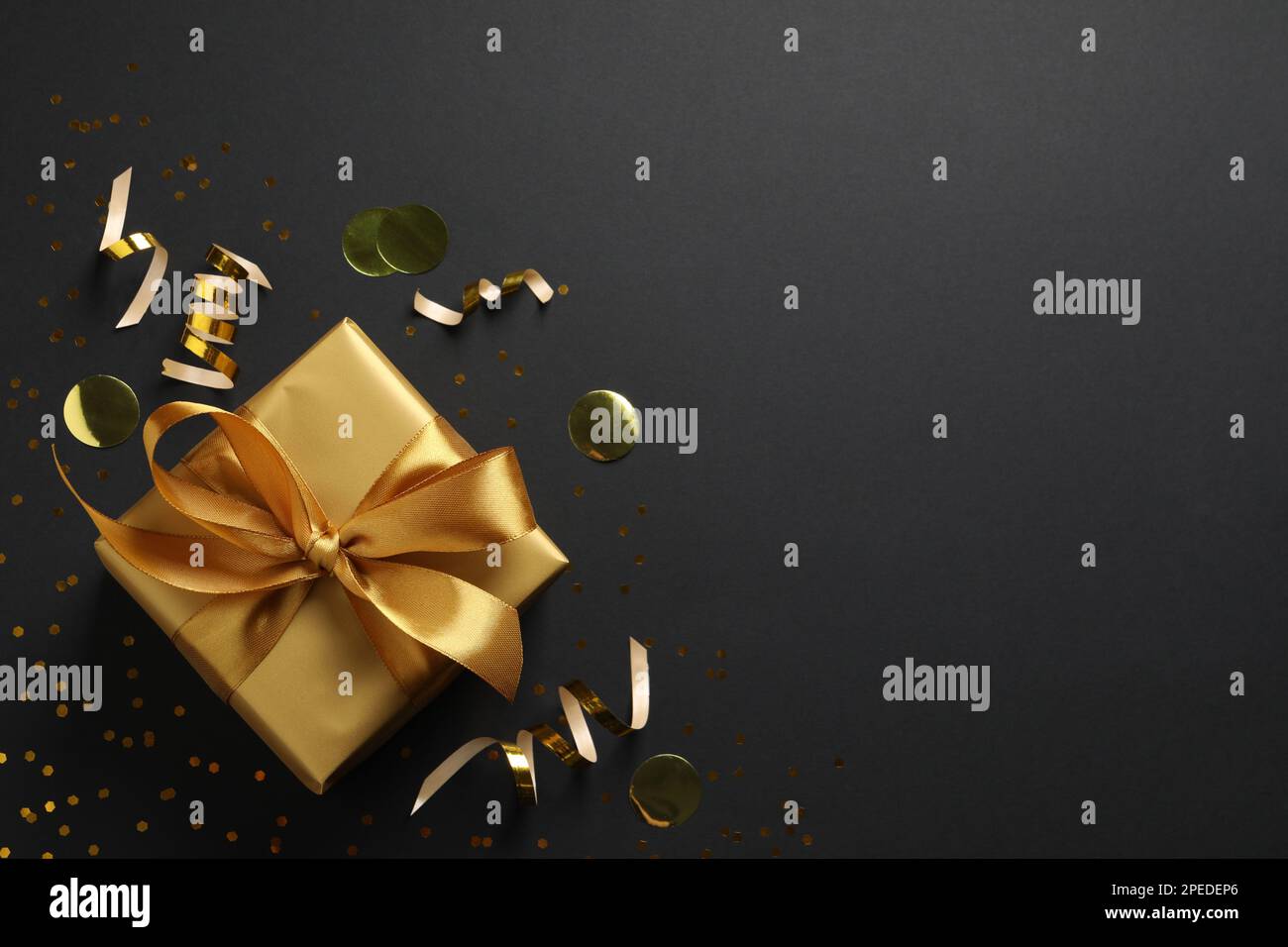 Golden gift box with confetti and streamers on black background, flat ...