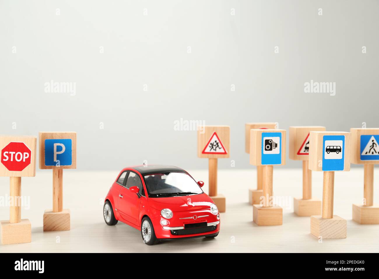 Many different miniature road signs and car on white wooden table ...