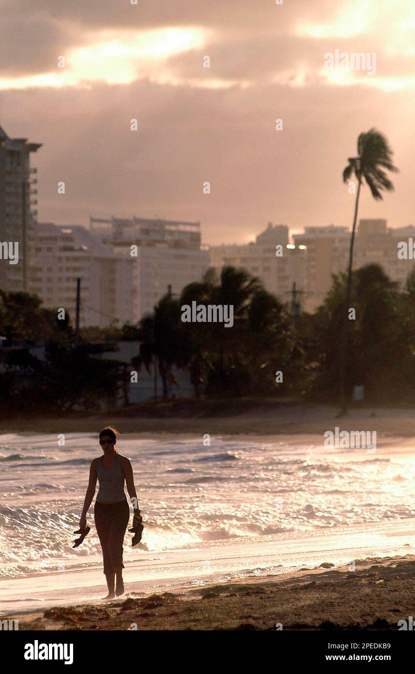 A woman takes a morning walk in Ocean Park Beach in San Juan, Puerto ...
