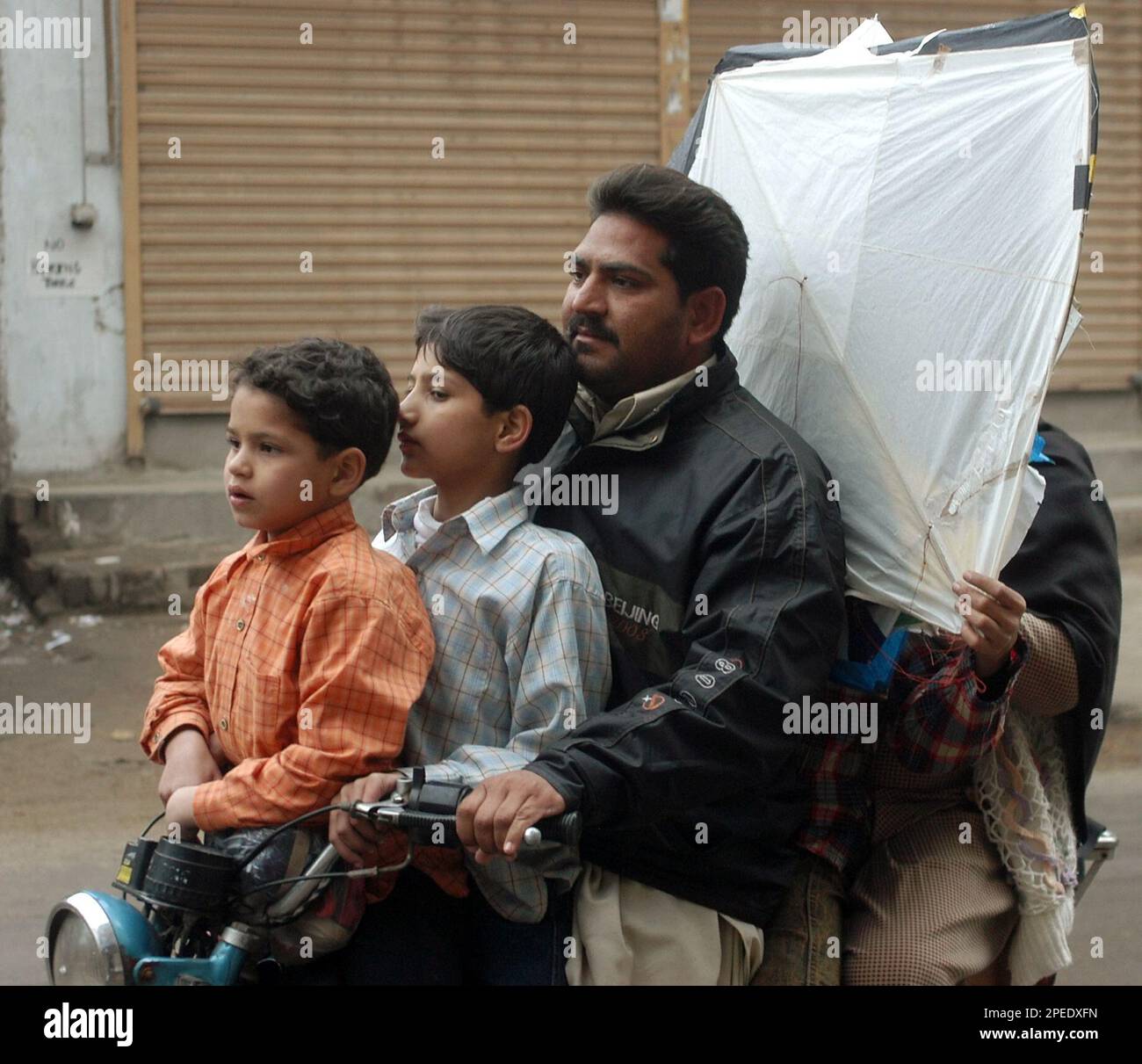 Pakistani adults and children ride a motorcycle on their way to take ...