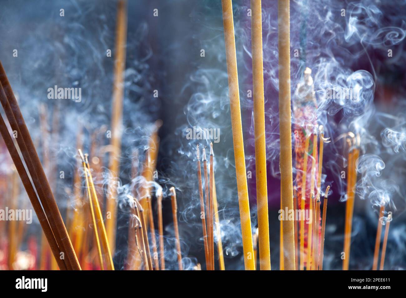 Many scented incense sticks burning in a Buddhist shrine, creating a fragrant and smoky ...