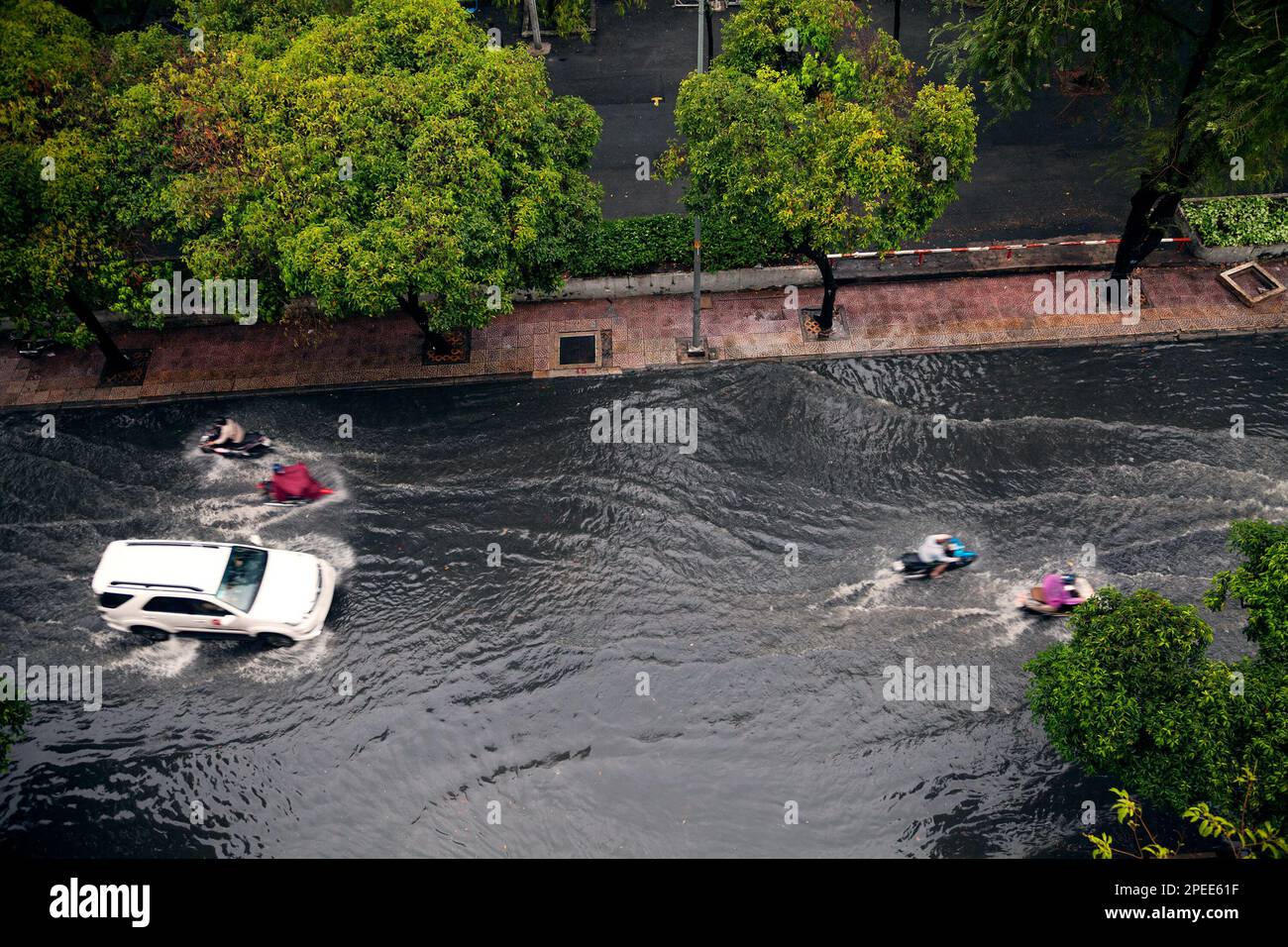 Street flood after a heavy rain in an Asian city. Car and motorbikes ...