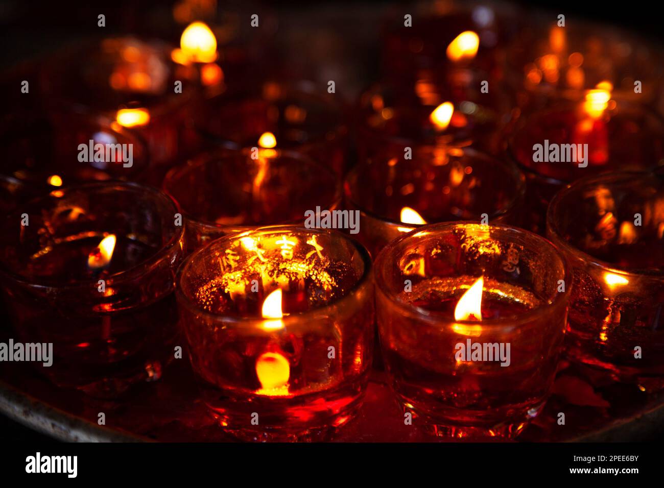 Close-up photo of a lot of red candles in glasses burning in a Chinese ...
